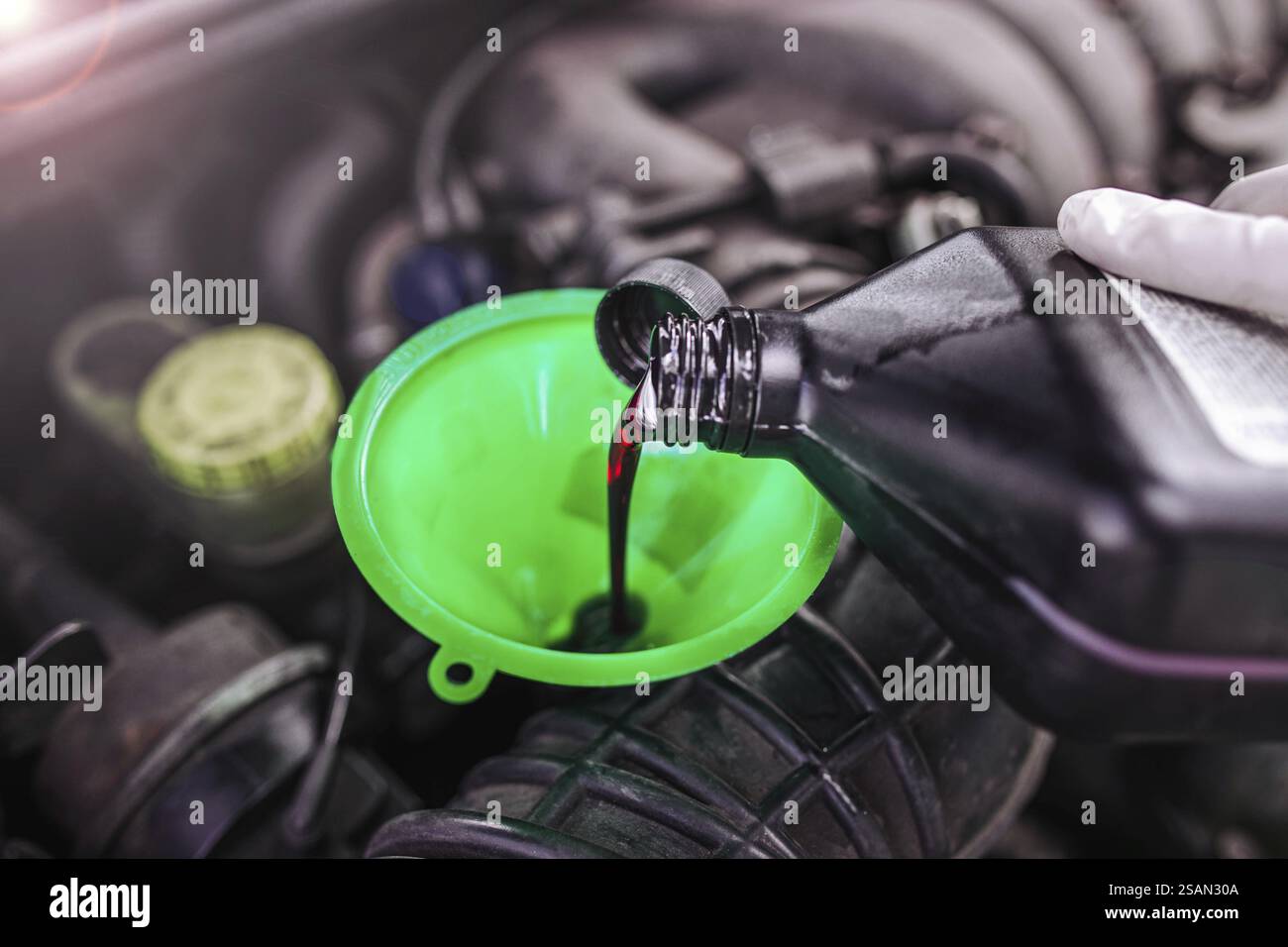 Liquids being poured into a car engine through a green funnel Stock ...