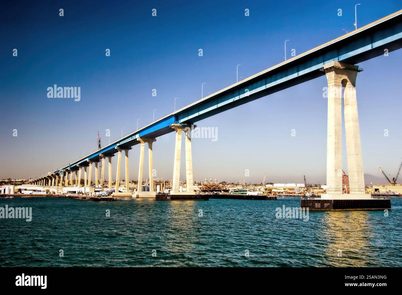 A large bridge spans a body of water. The bridge is blue and white. The ...