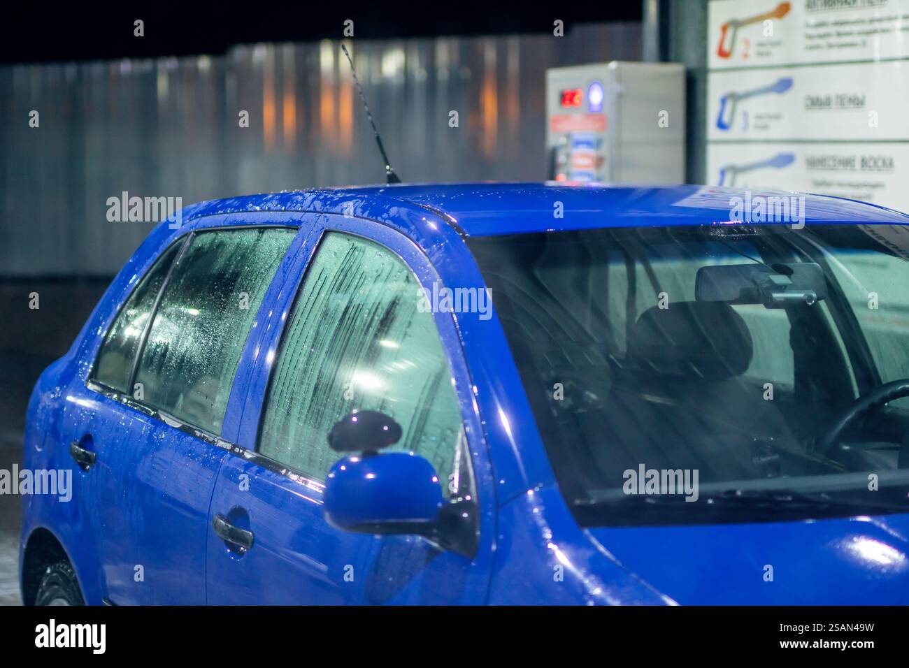 This is a detailed closeup view of the shiny side mirror of a blue car ...