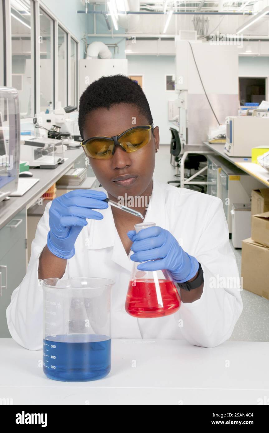 Beautiful woman scientist investigating a glass beaker Stock Photo - Alamy