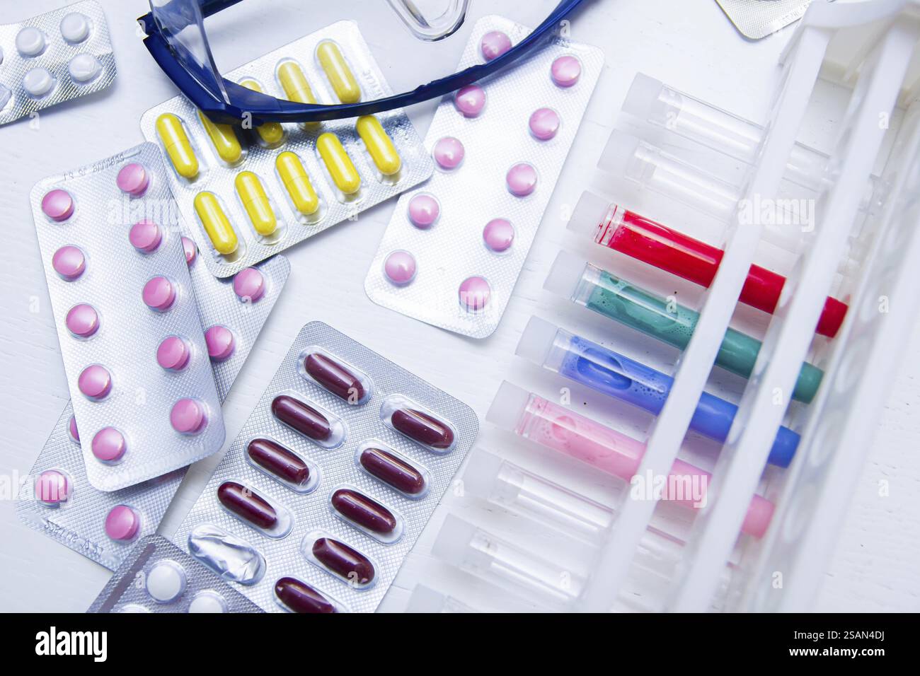 Variety of pills and colorful test tubes on a lab desk, surrounded by ...
