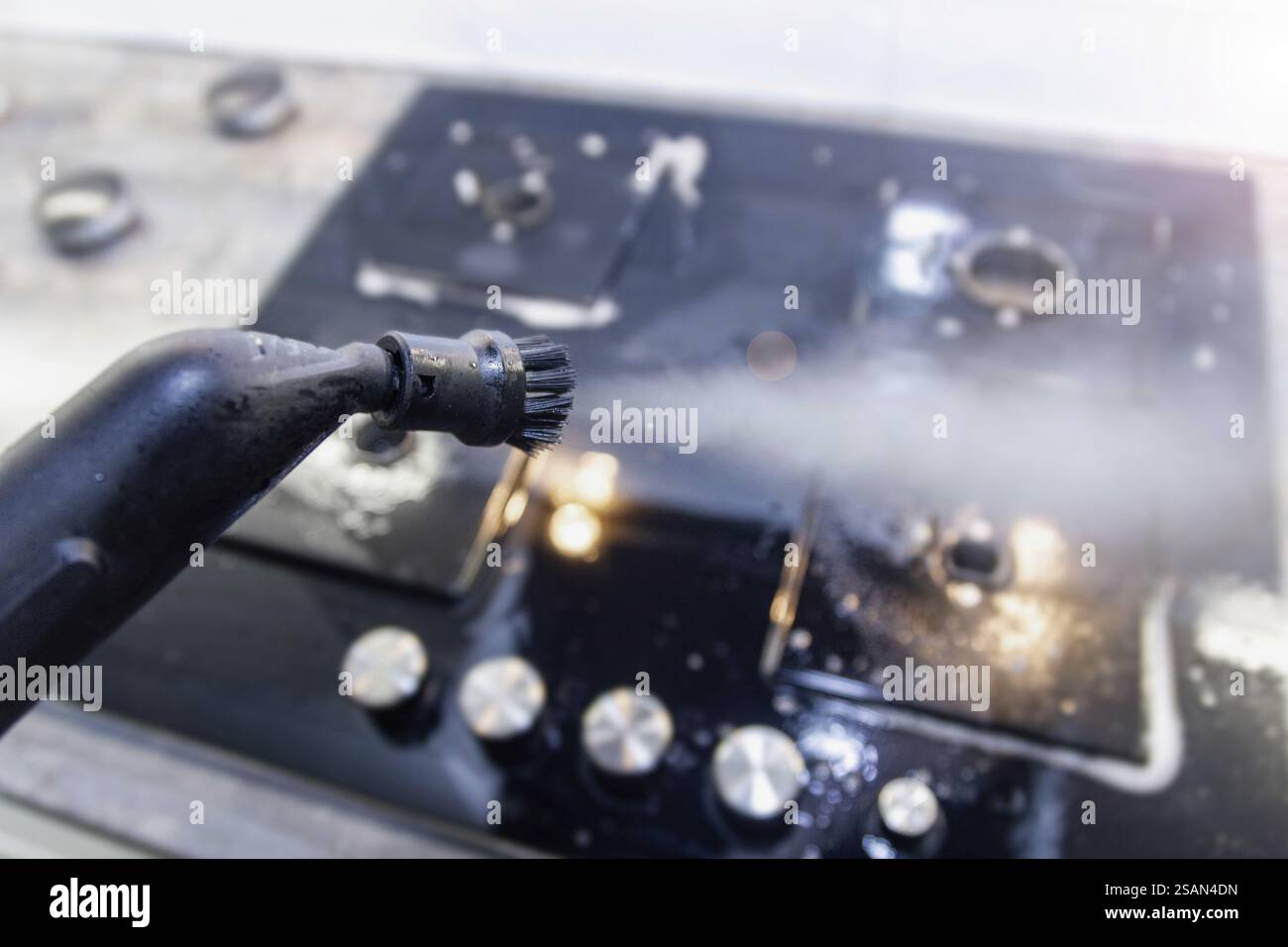 Nozzle spraying steam onto a black stovetop, creating a misty effect ...