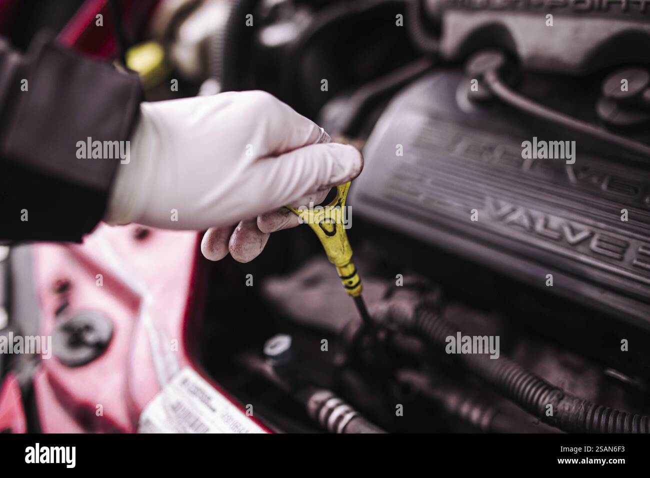 Hand with glove holding an oil dipstick in a car engine bay Stock Photo ...