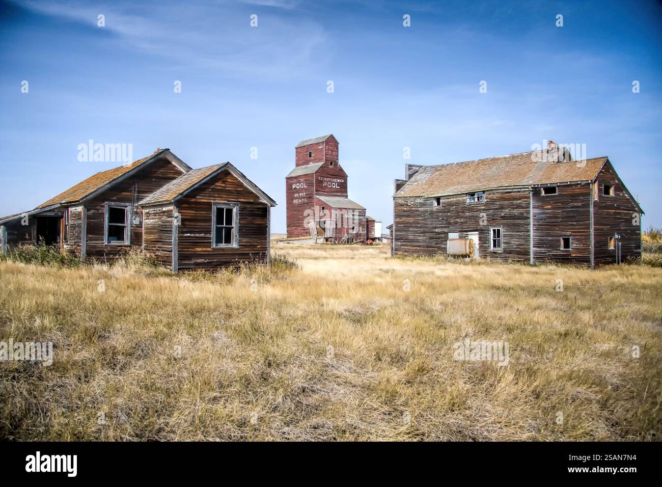 A farm with three old buildings and a red grain silo. The buildings are ...