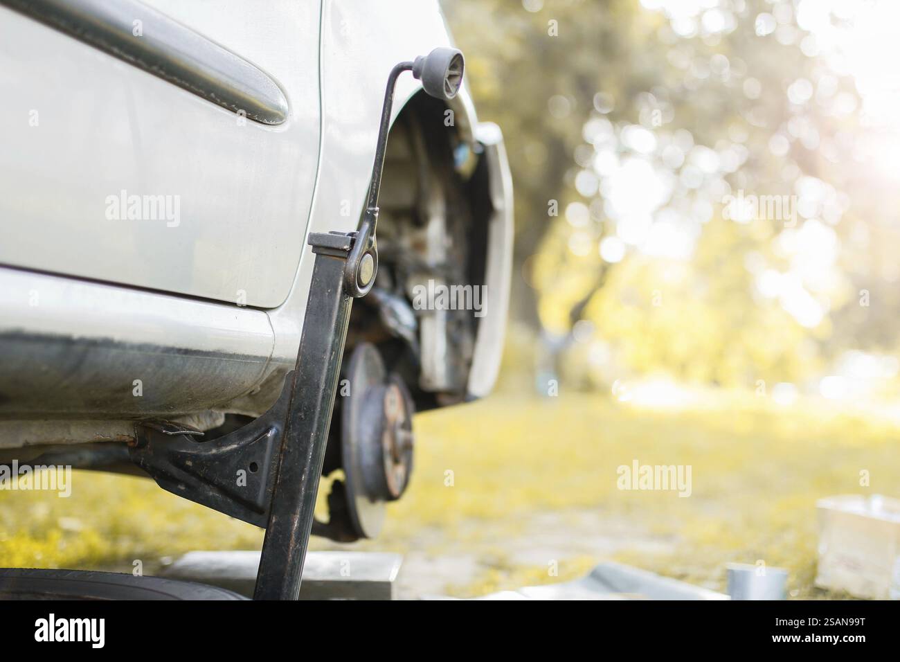A car lifted on a jack in a sunny setting with visible repair progress ...