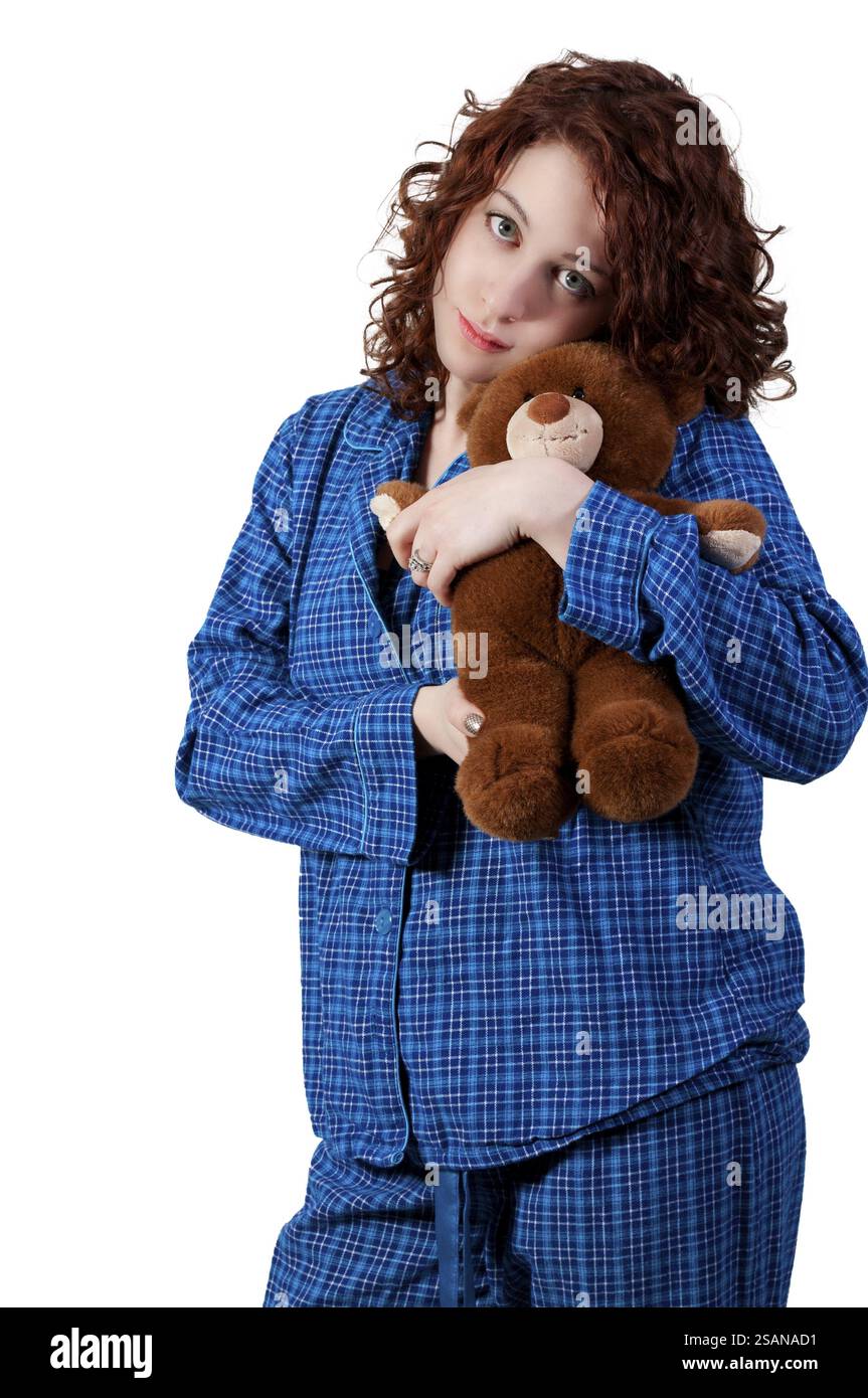 A beautiful young woman wearing pajamas hugging her stuffed teddy bear ...