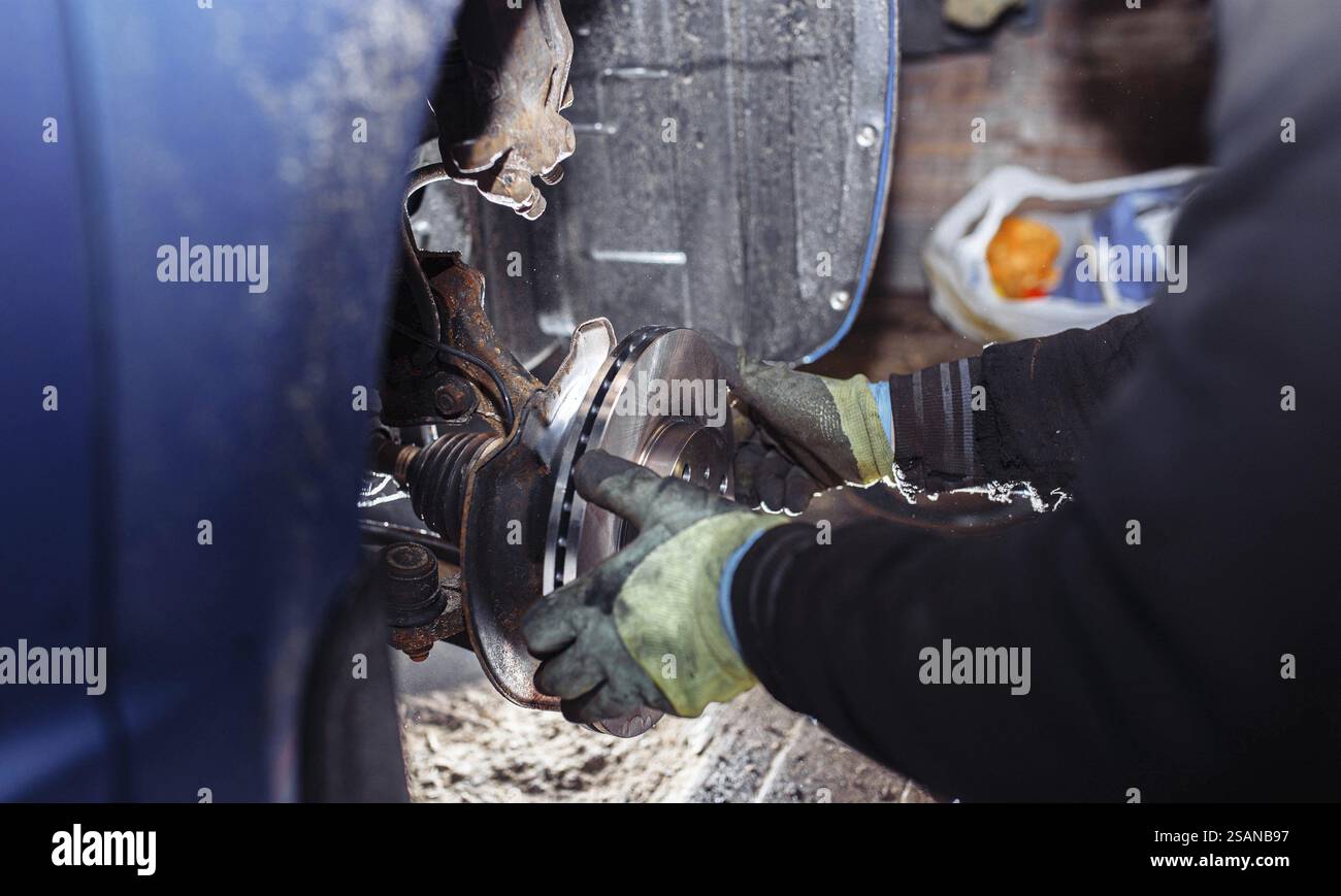 Mechanic's hands working on a car brake disc, maintenance in progress ...