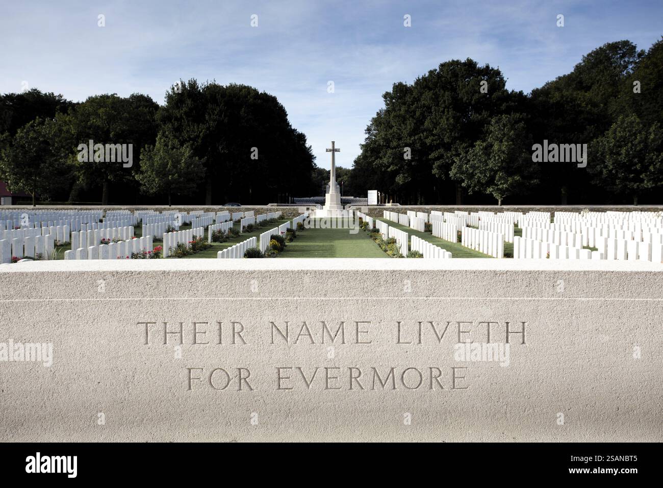 A peaceful cemetery with rows of white headstones and a central cross ...