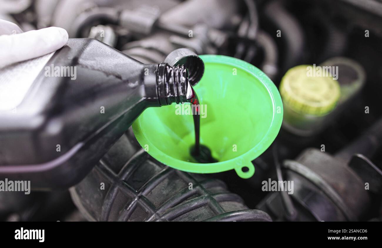 Pouring engine oil into a car engine using a green funnel Stock Photo ...