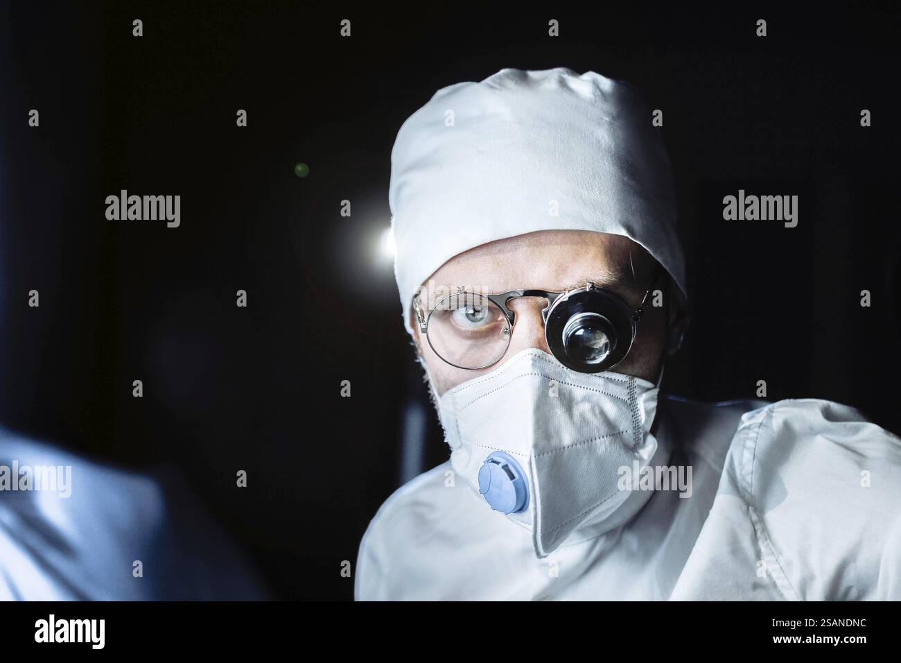 Doctor with monocle and intense gaze, wearing protective gear in a dark ...