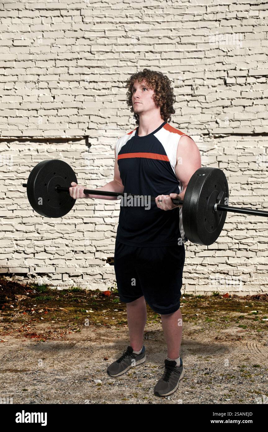 Handsome young muscular man lifting a weight Stock Photo - Alamy