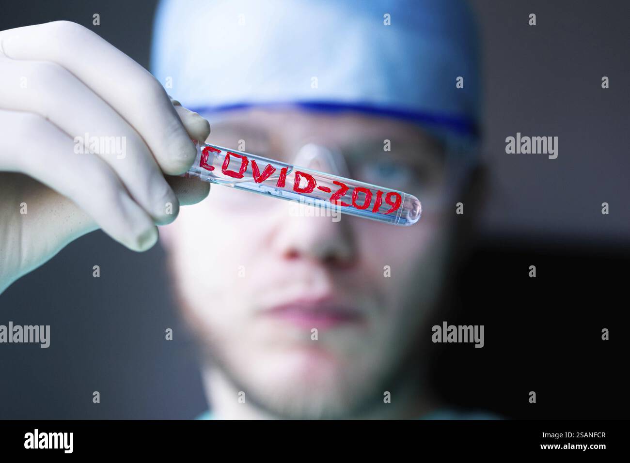Person with test tube labeled COVID-2019, wearing medical attire Stock ...