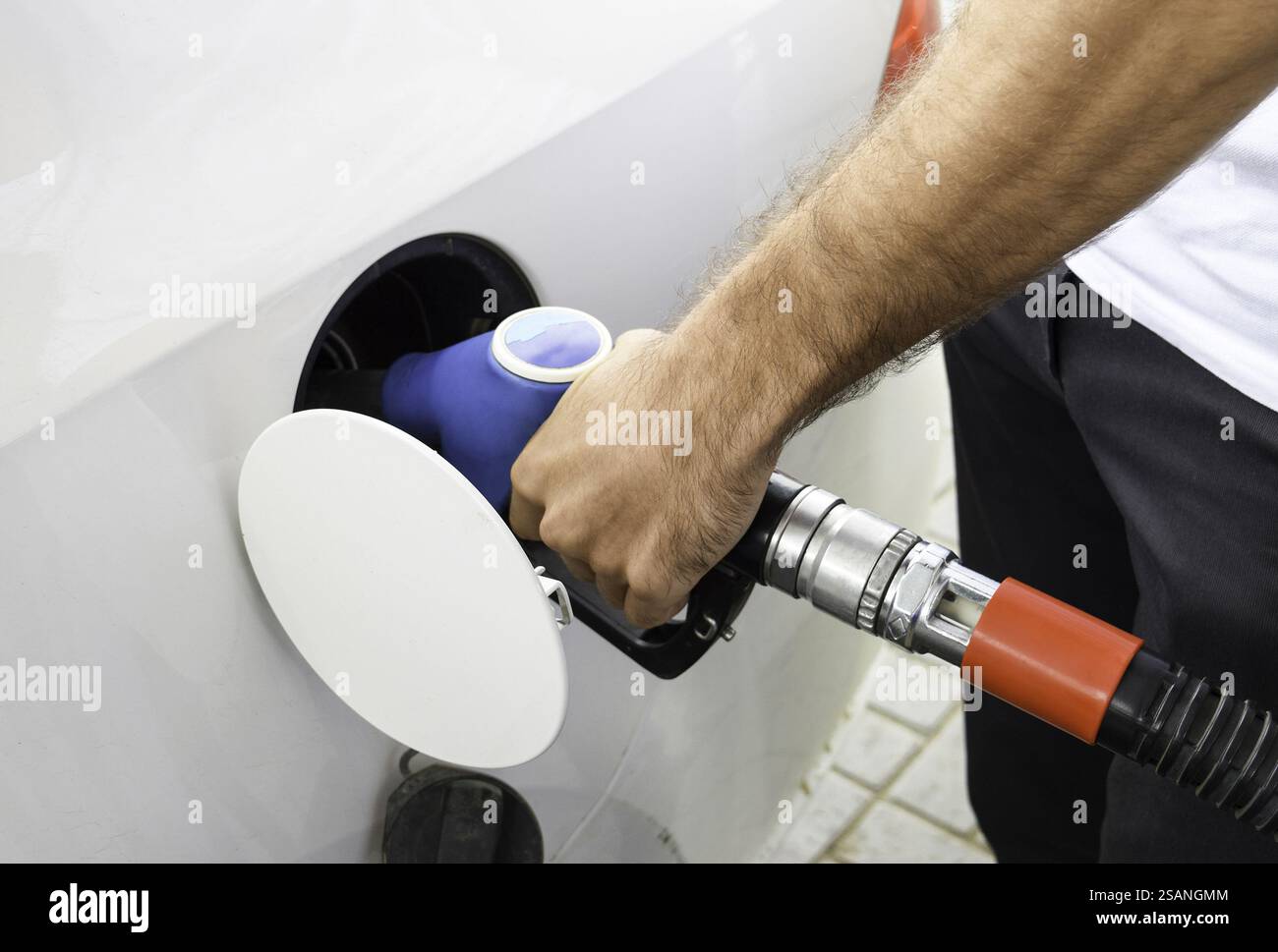 Filling a car with gasoline, the nozzle is inserted into the gas tank ...
