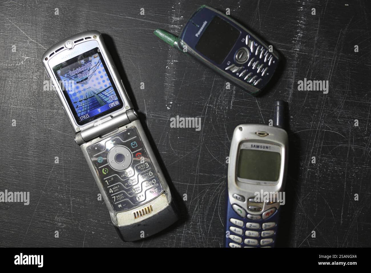 Three retro mobile phones including a Motorola flip phone on a black ...