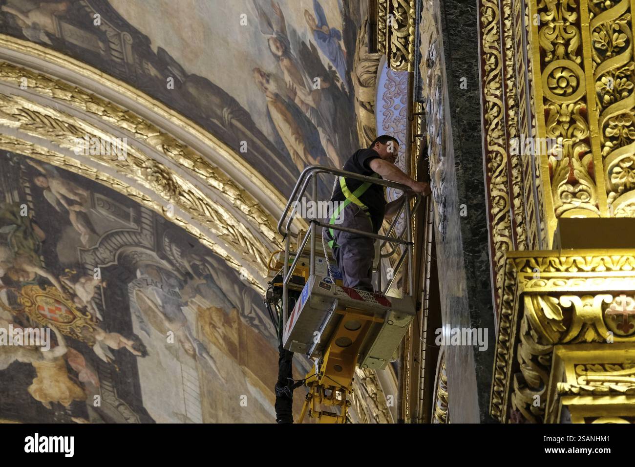 Worker restores an ornate mural on a gold-embellished ceiling, using ...
