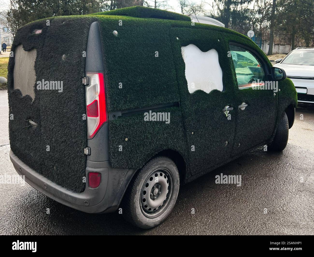 A van entirely covered with artificial grass parked outdoors ...