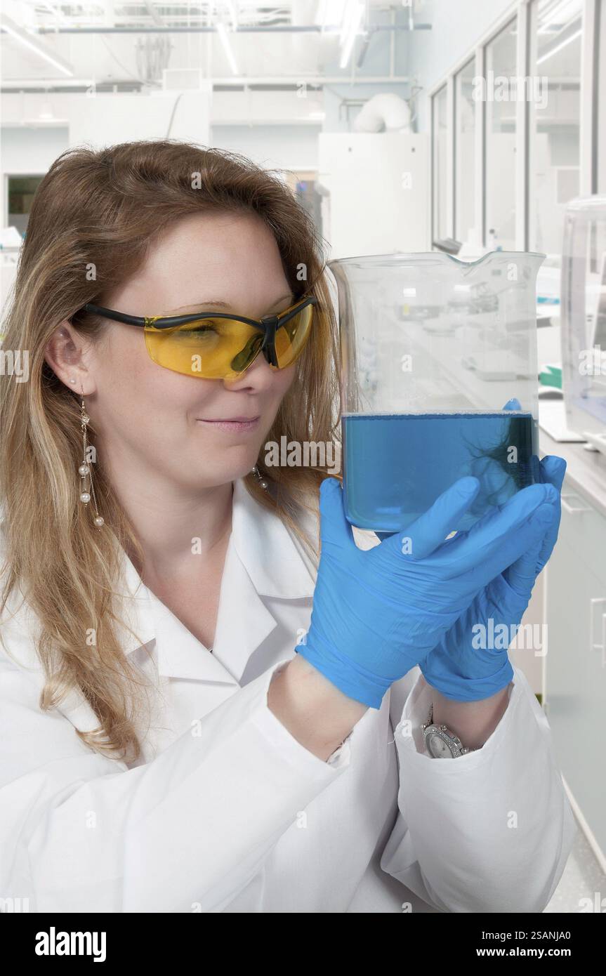 Beautiful woman scientist investigating a glass beaker Stock Photo - Alamy