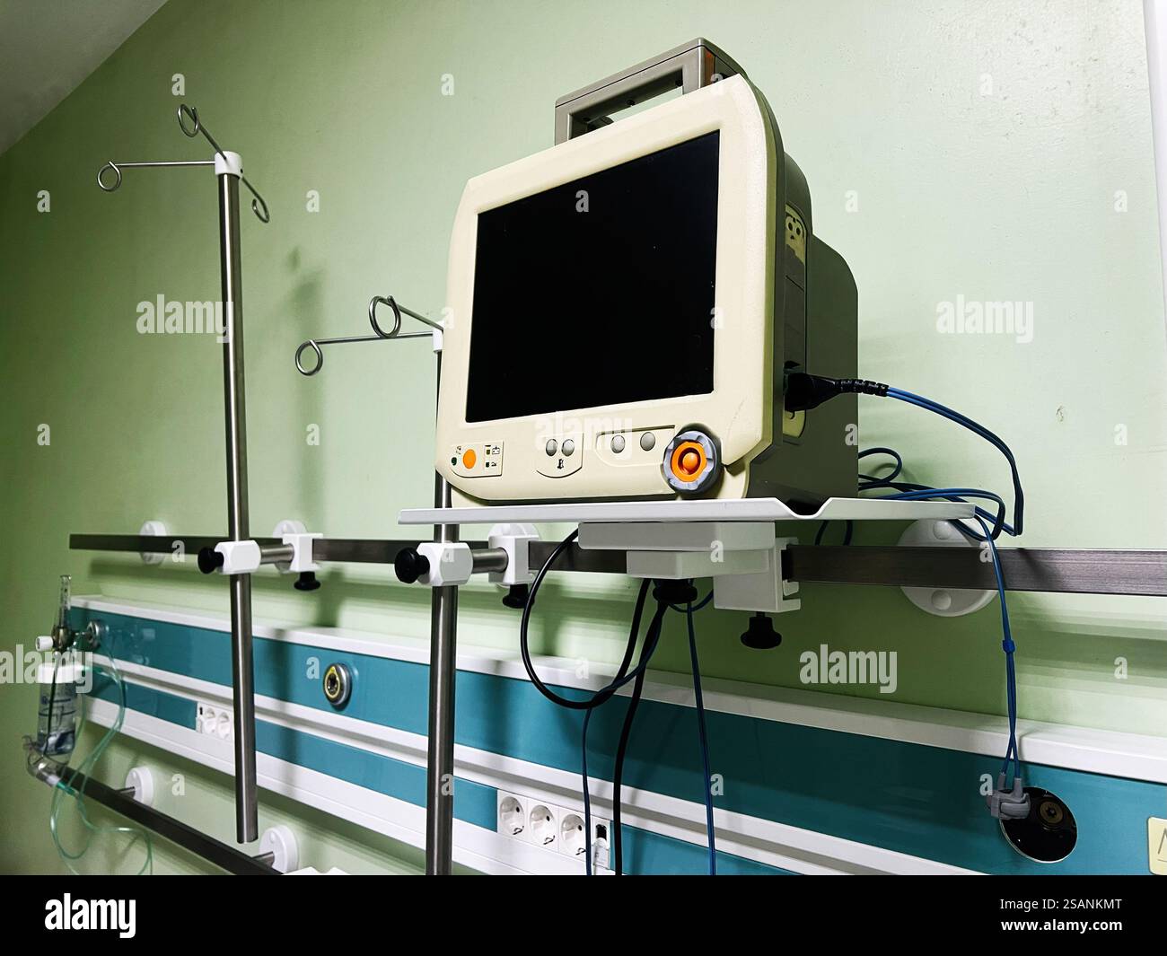 A hospital room featuring a medical monitor mounted on a wall with ...