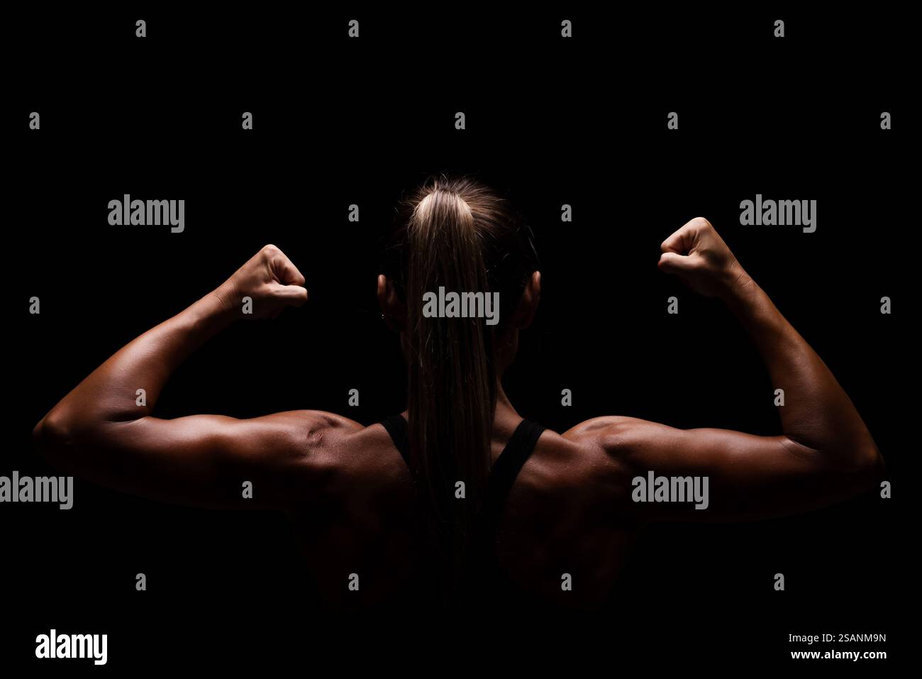 Muscular woman from behind flexing her arms, emphasizing strength and ...