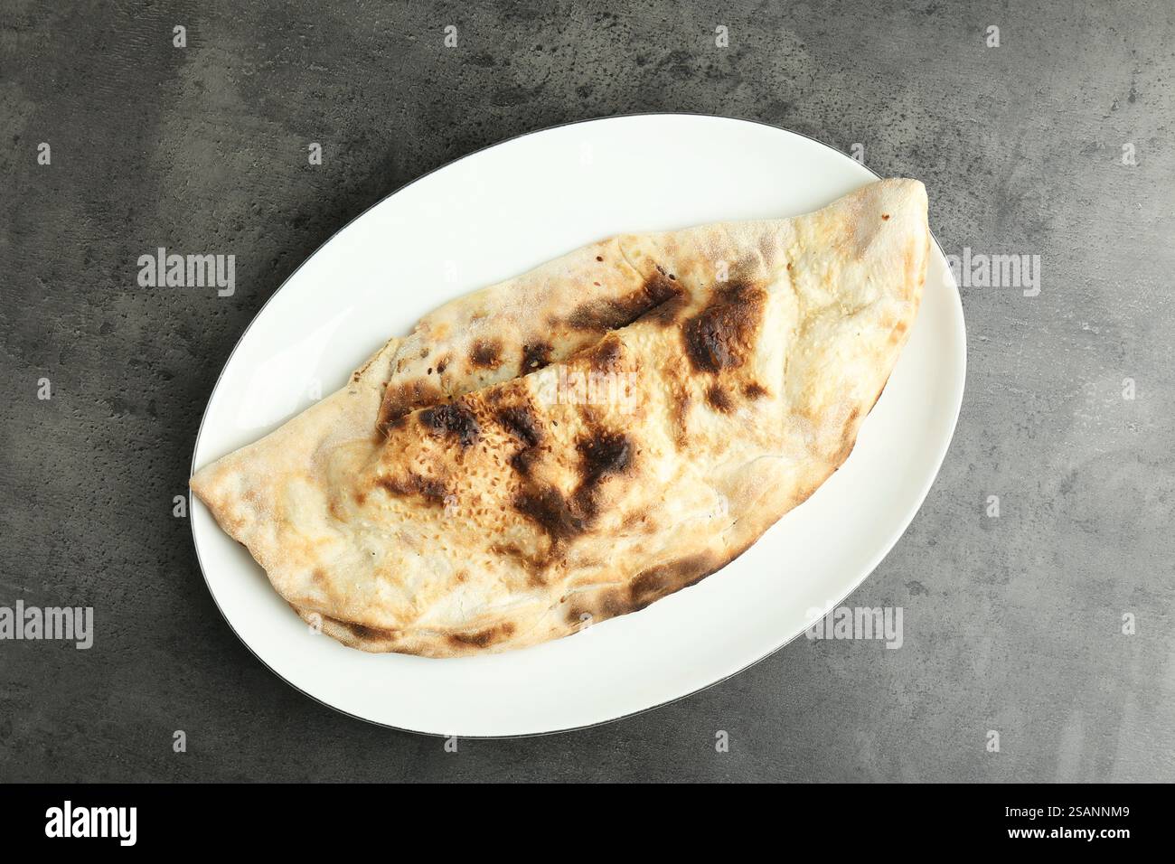 One delicious calzone on grey textured table, top view Stock Photo - Alamy