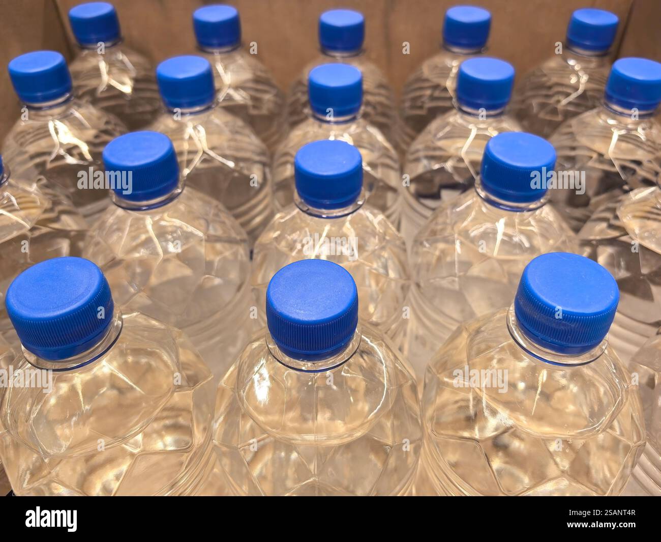 Clear bottles with blue caps are neatly lined up in a store, showcasing ...