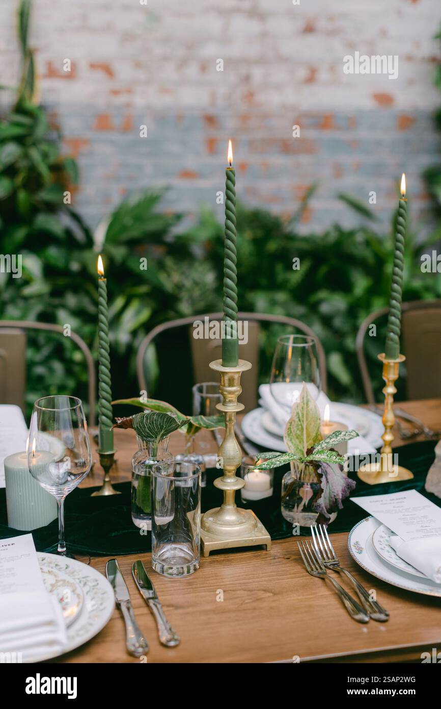 A beautifully arranged dining table with tall green candles, glassware ...
