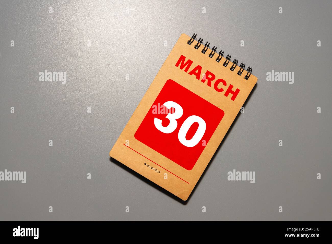 Wooden block calendar with date March 30 on blue yellow backround. Top ...