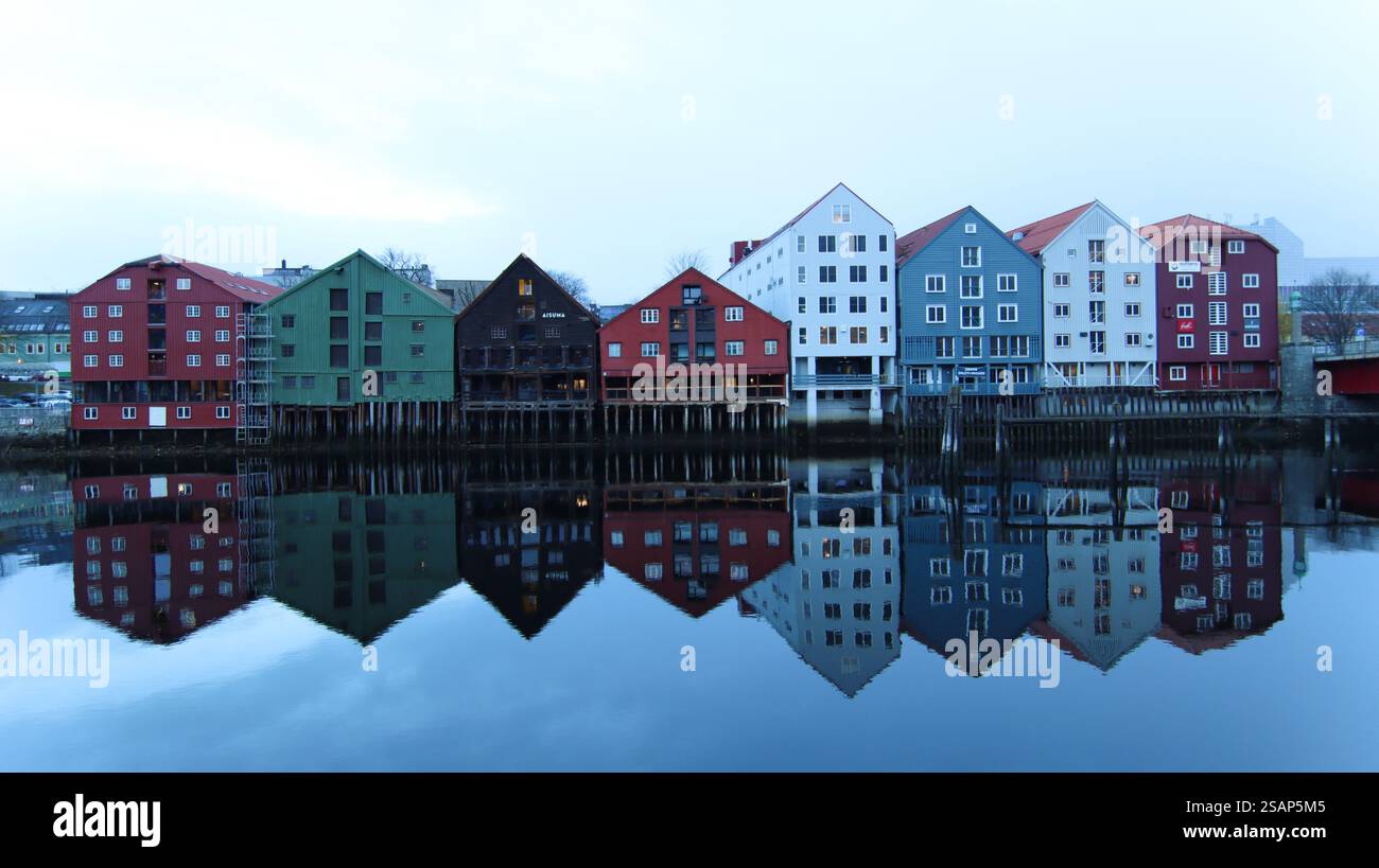 Colorful waterfront buildings reflect in calm water during twilight in ...