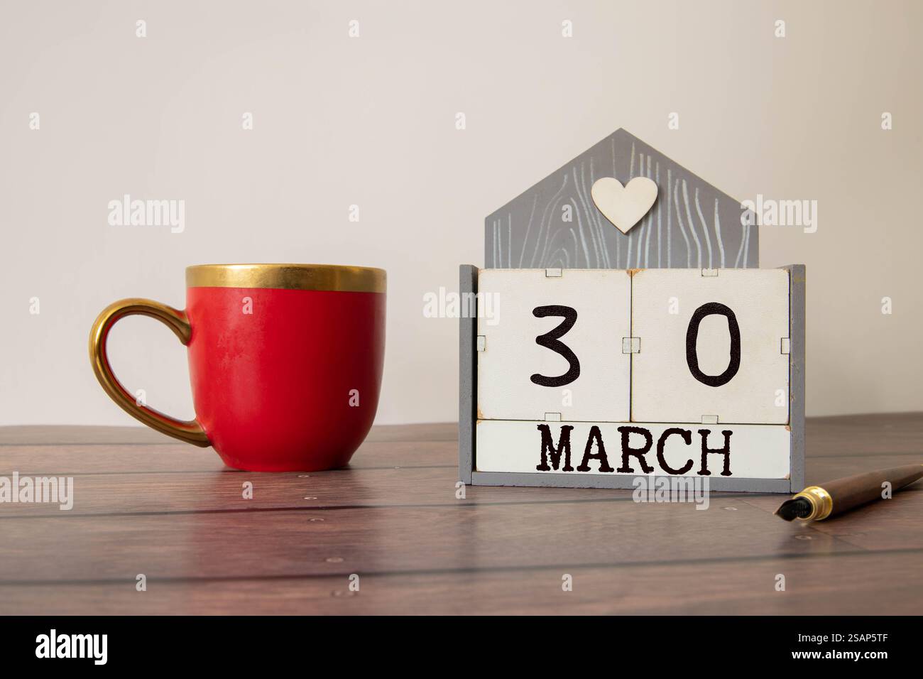 Wooden block calendar with date March 30 on blue yellow backround. Top ...