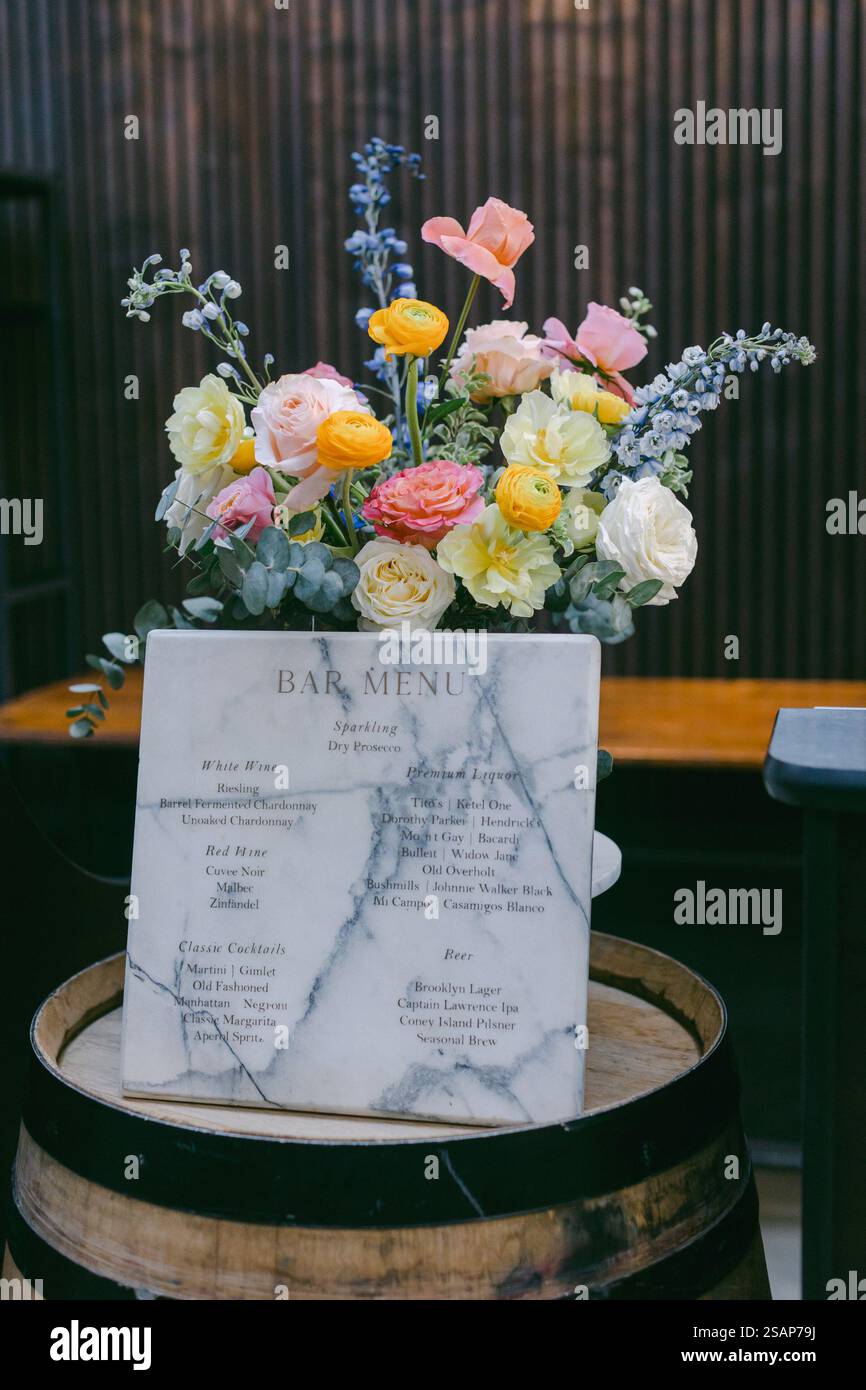 A beautifully arranged bar menu sits atop a wooden barrel, surrounded ...