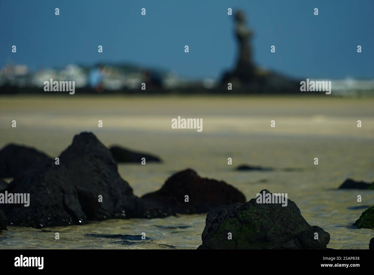 Small black stones and human-shaped stone statues at the beach in Jeju ...