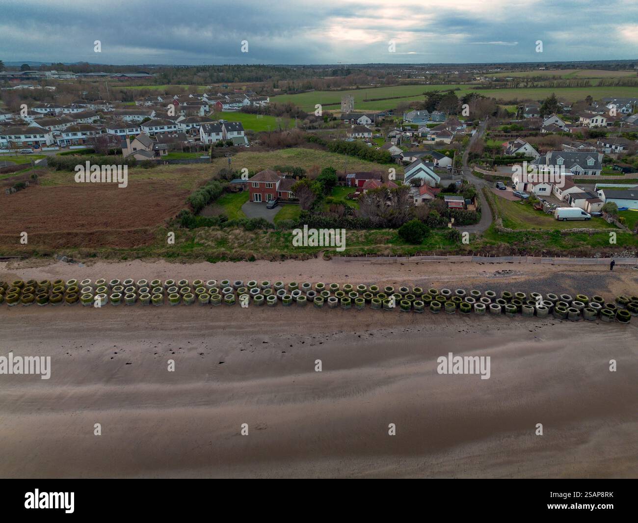 A beach with a row of cement blocks on the sand. There are several ...