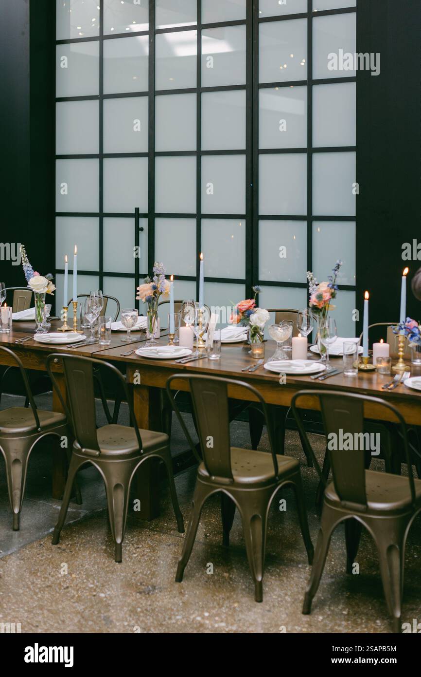 A long wooden dining table is set with various dishes, candles, and ...