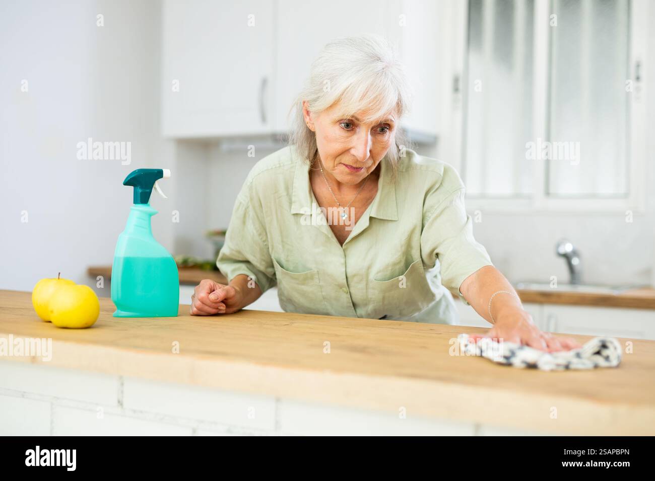 Old woman cleaning table with rag at home Stock Photo - Alamy