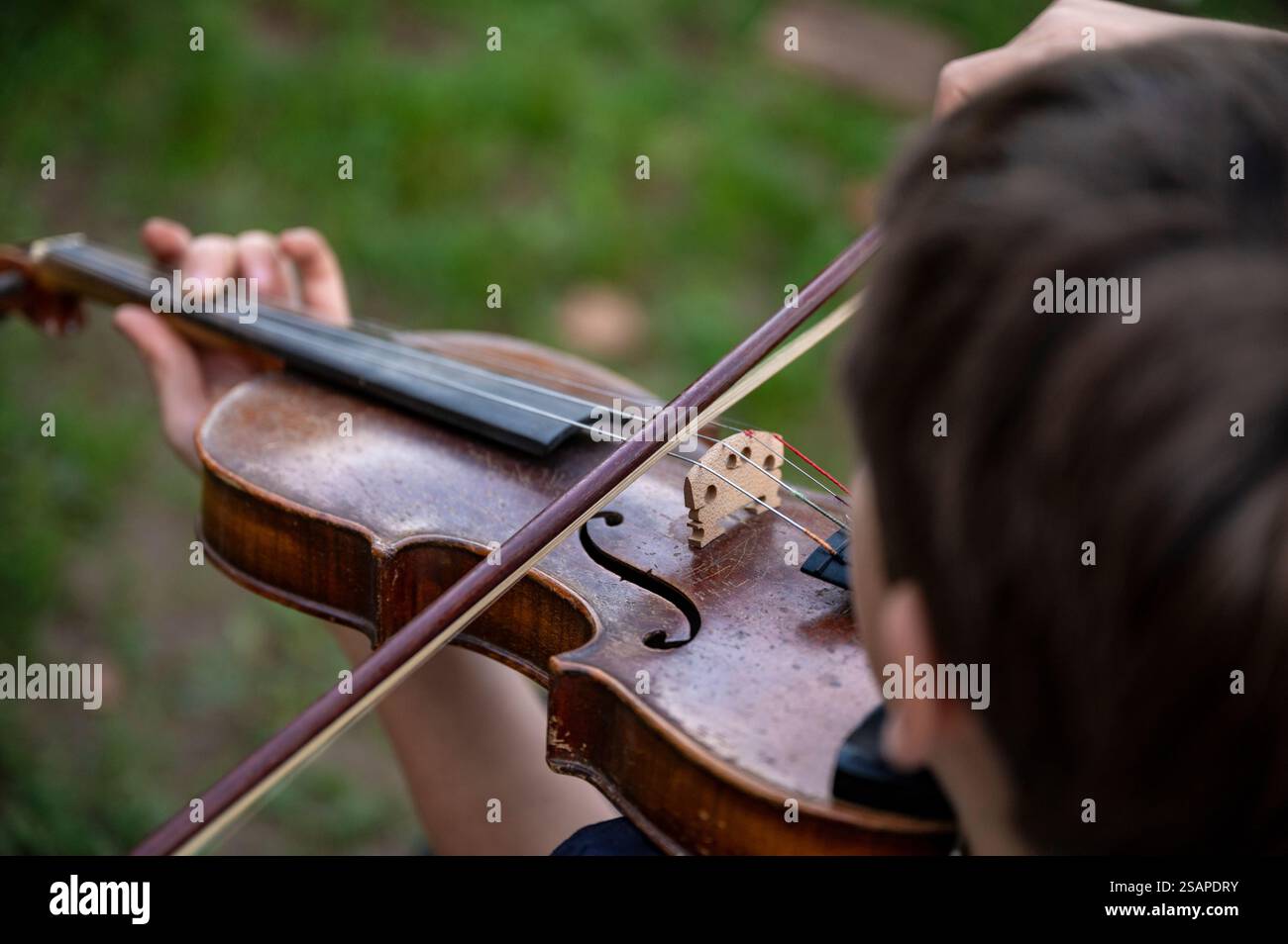 Over the shoulder view of a boy practicing playing classical violin ...