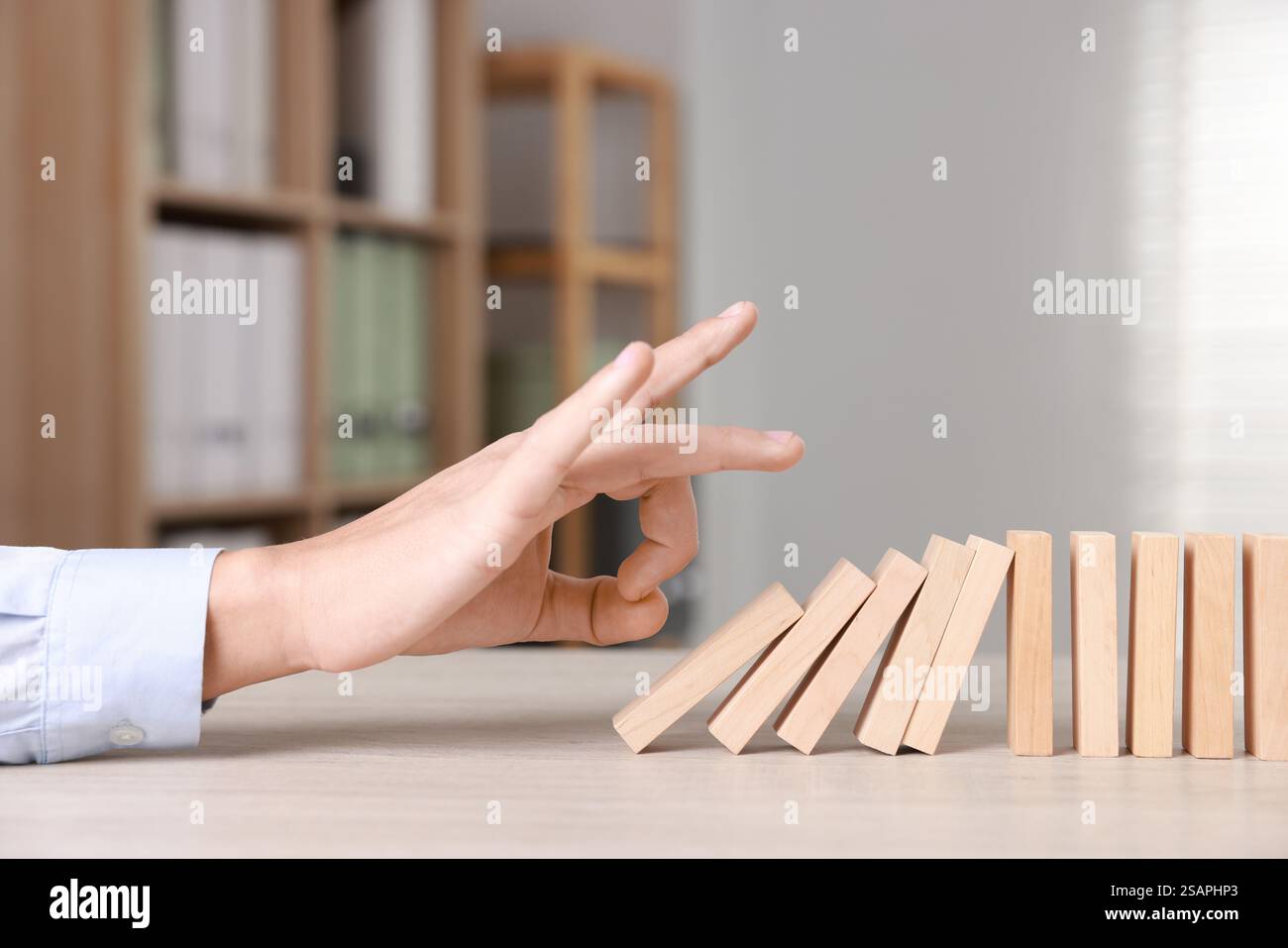 Domino effect. Man pushing wooden blocks at table, closeup Stock Photo ...