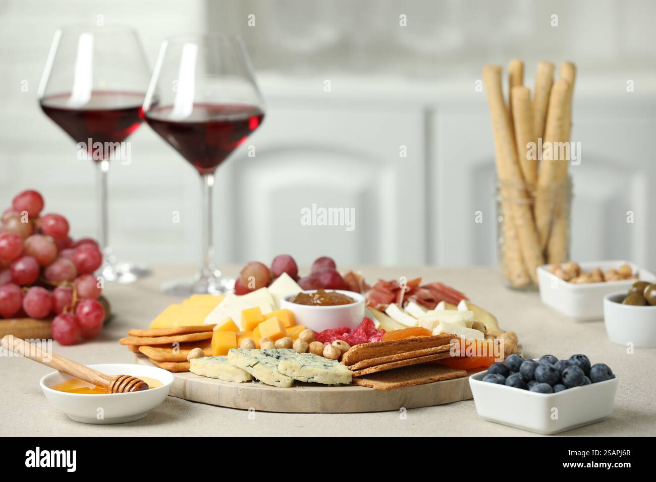 Different types of cut cheese and other snacks on light textured table ...