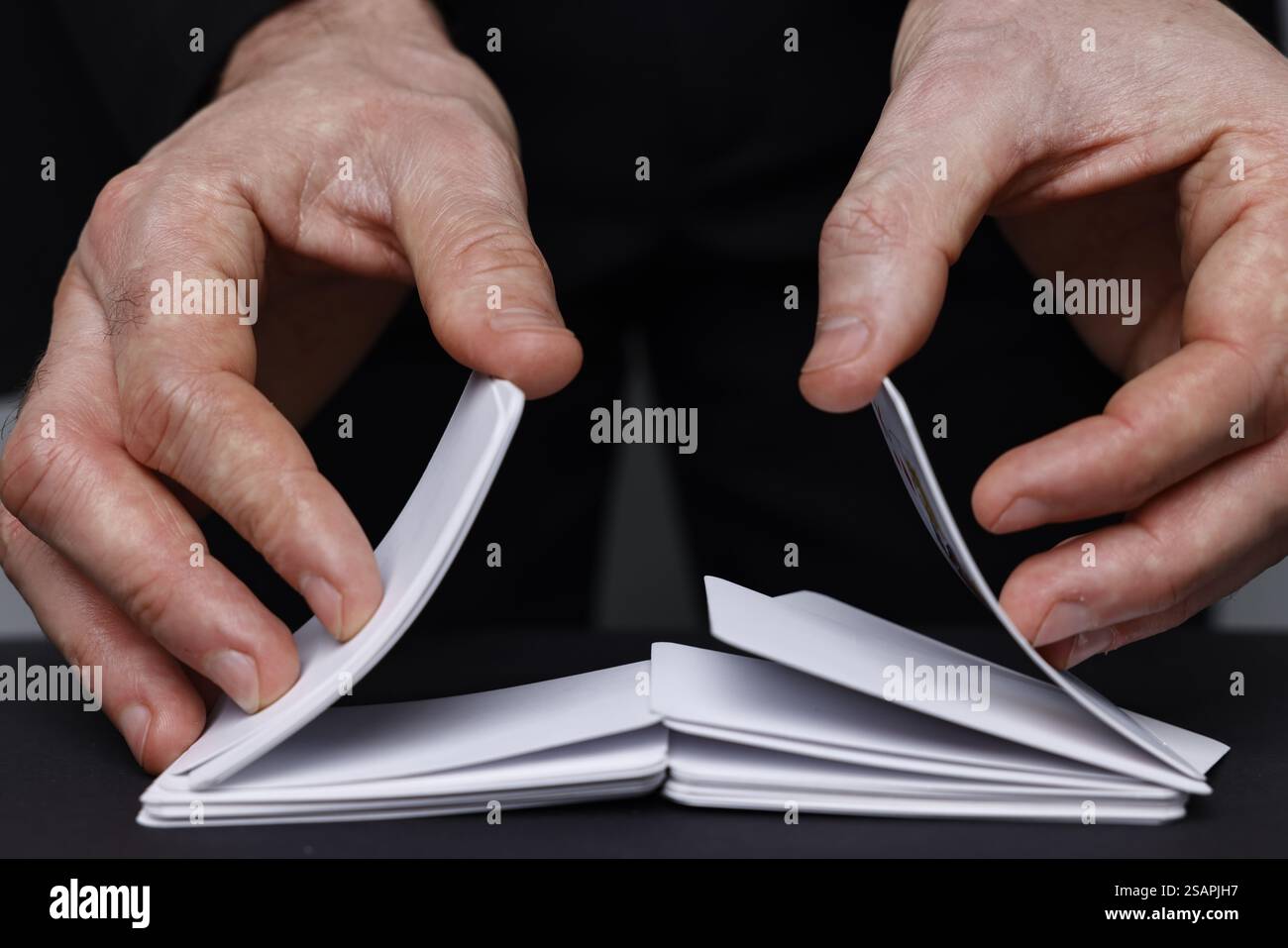 Illusionist shuffling playing cards at black table, closeup Stock Photo ...
