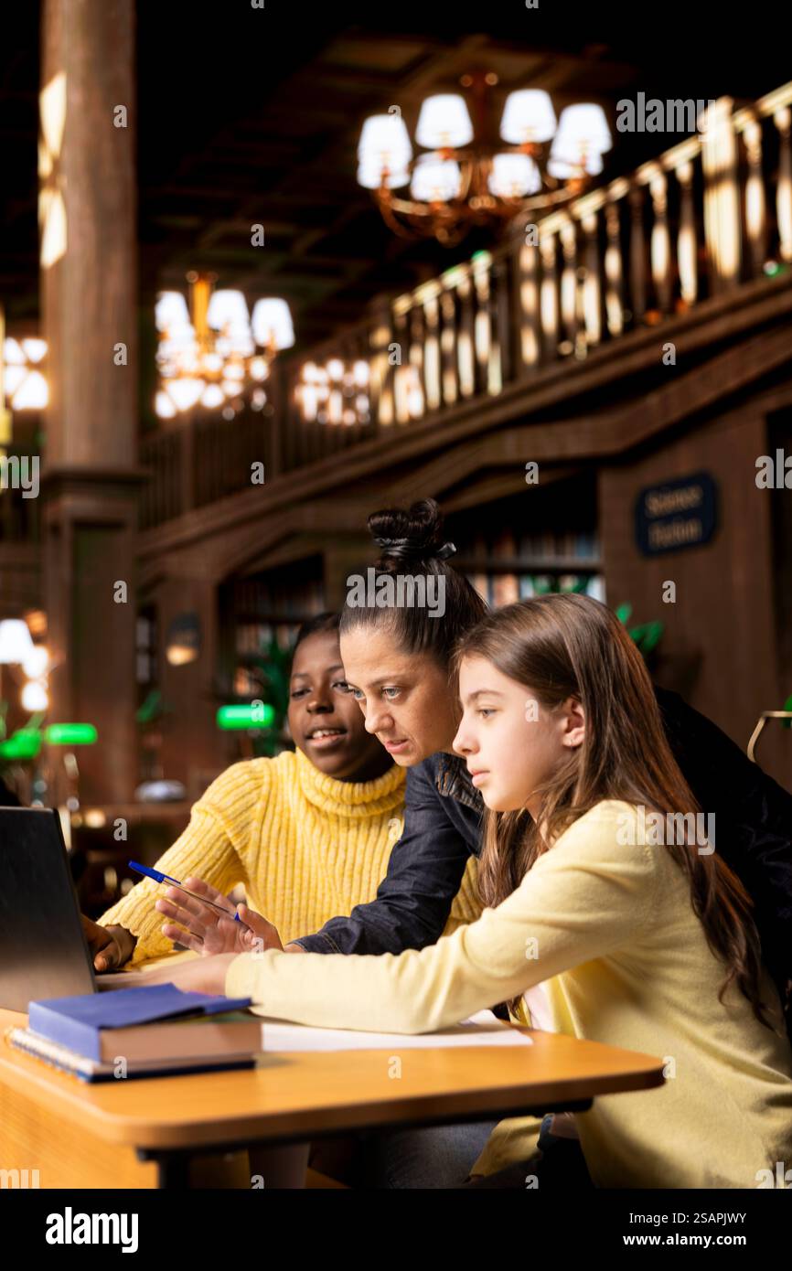 Elementary students receiving support from a tutor working on homework assignments together in a ...