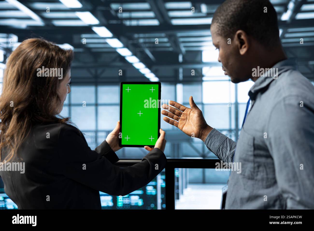 Team of engineers working in server farm, using chroma key tablet to analyze data. Employees ...