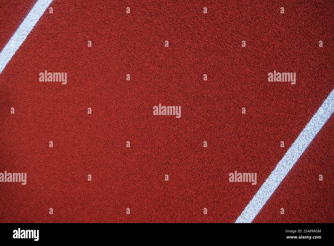 Red athletic track surface featuring white lane markings under a clear ...