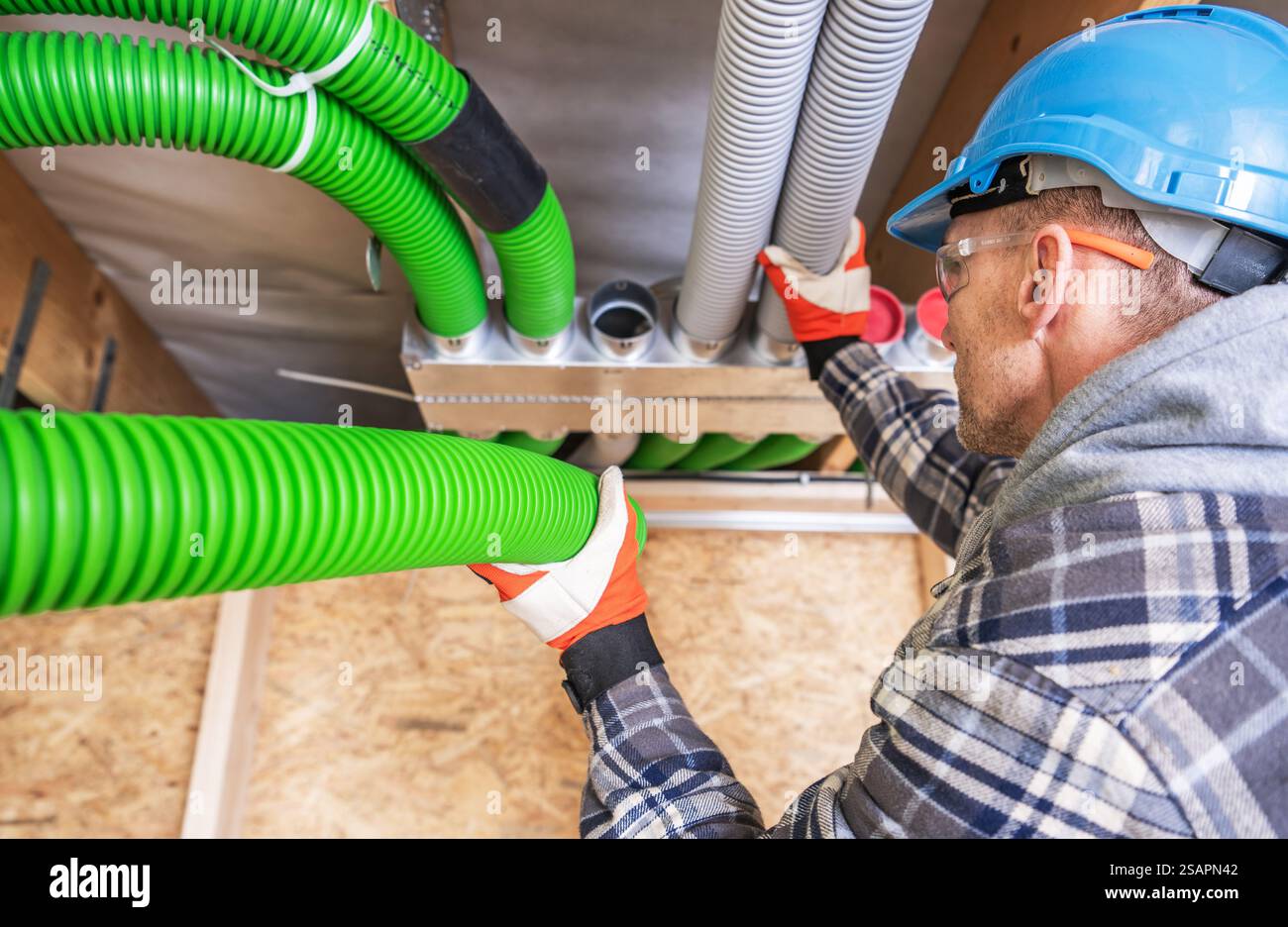 A construction worker in a blue hard hat connects bright green ...