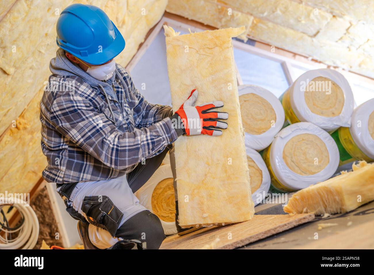 A construction worker is carefully installing insulation materials in a ...