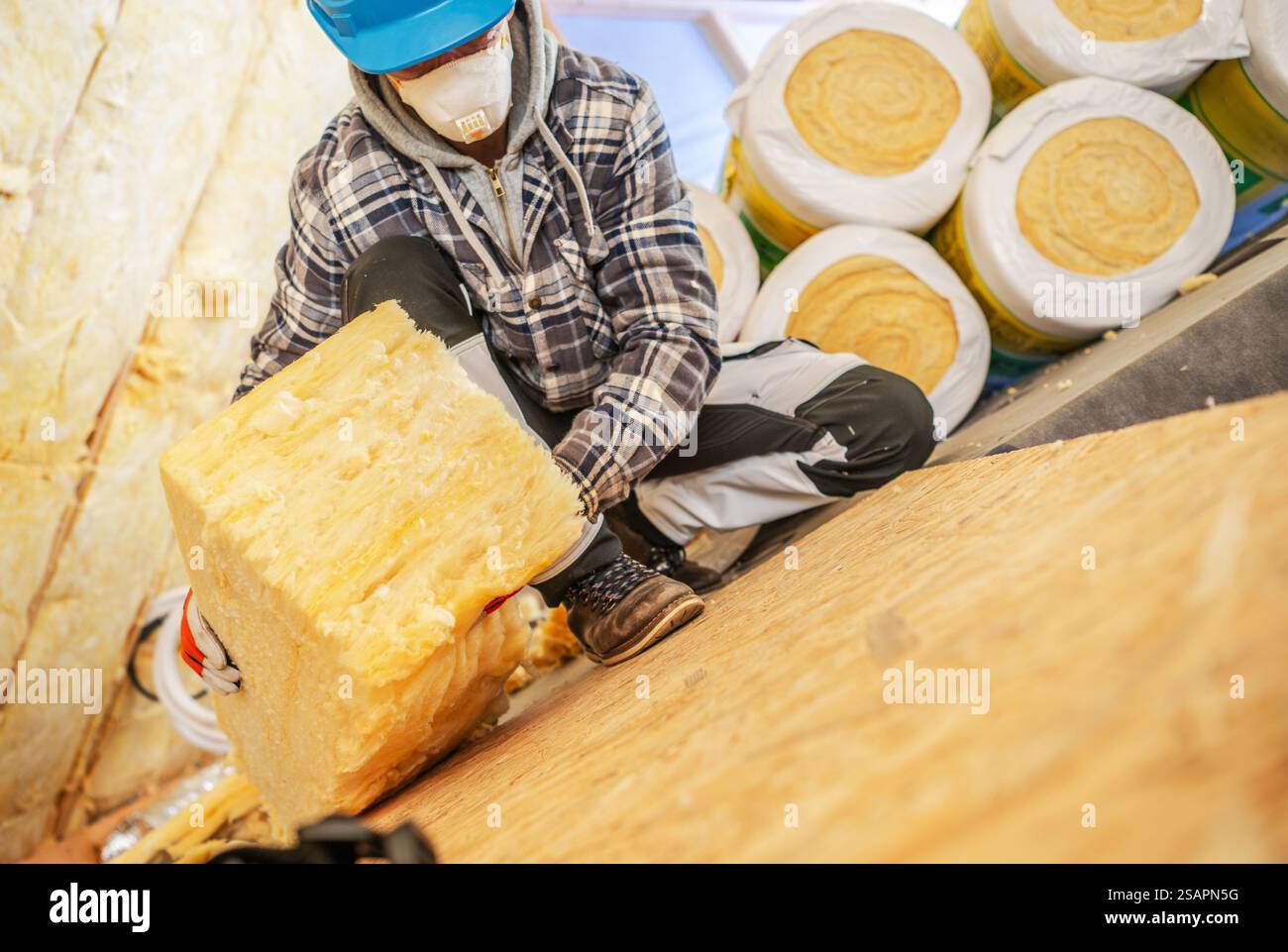 A construction worker carefully places a large block of insulation in ...