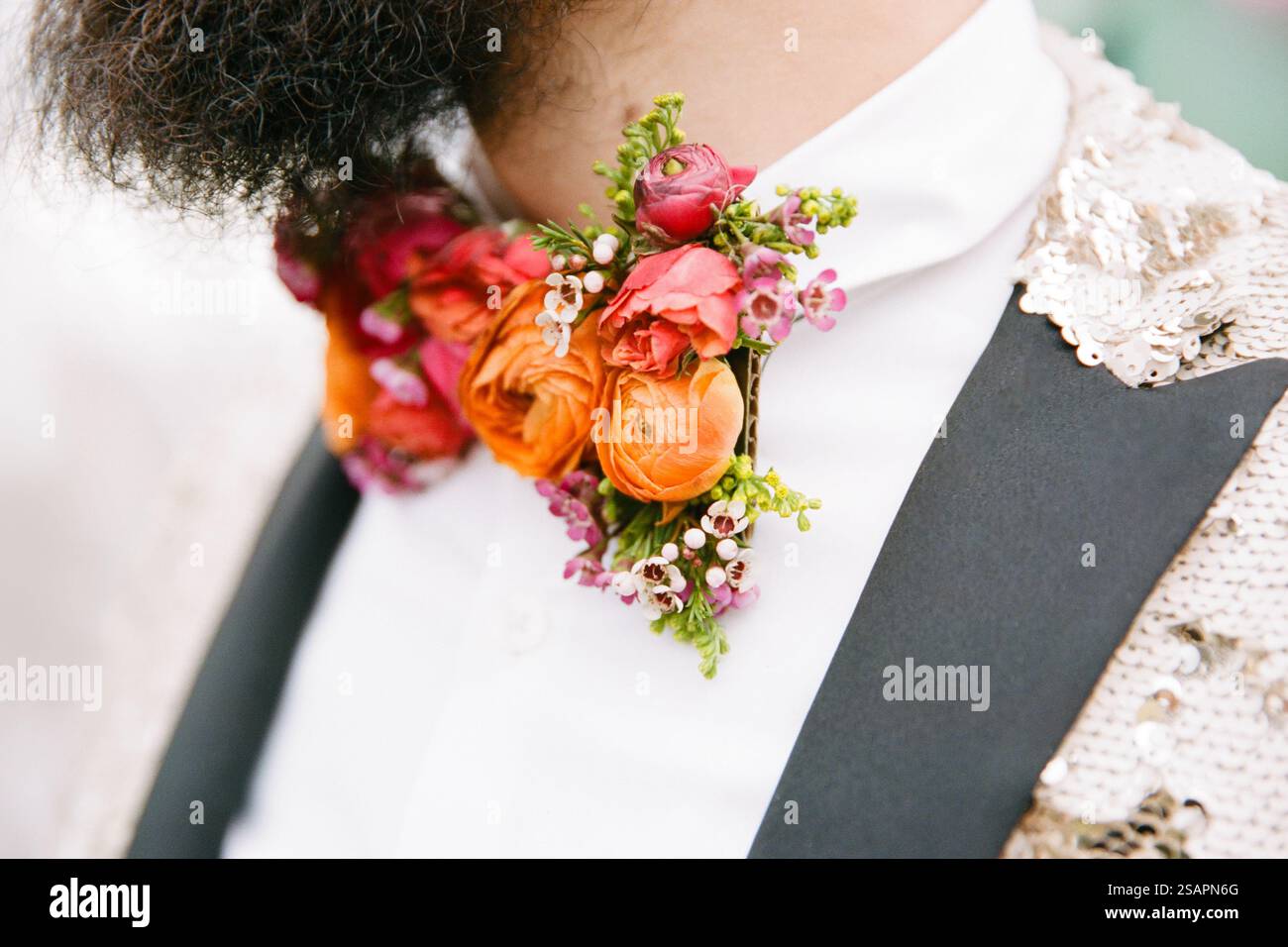 A groom showcases a stylish floral bowtie adorned with vibrant roses ...