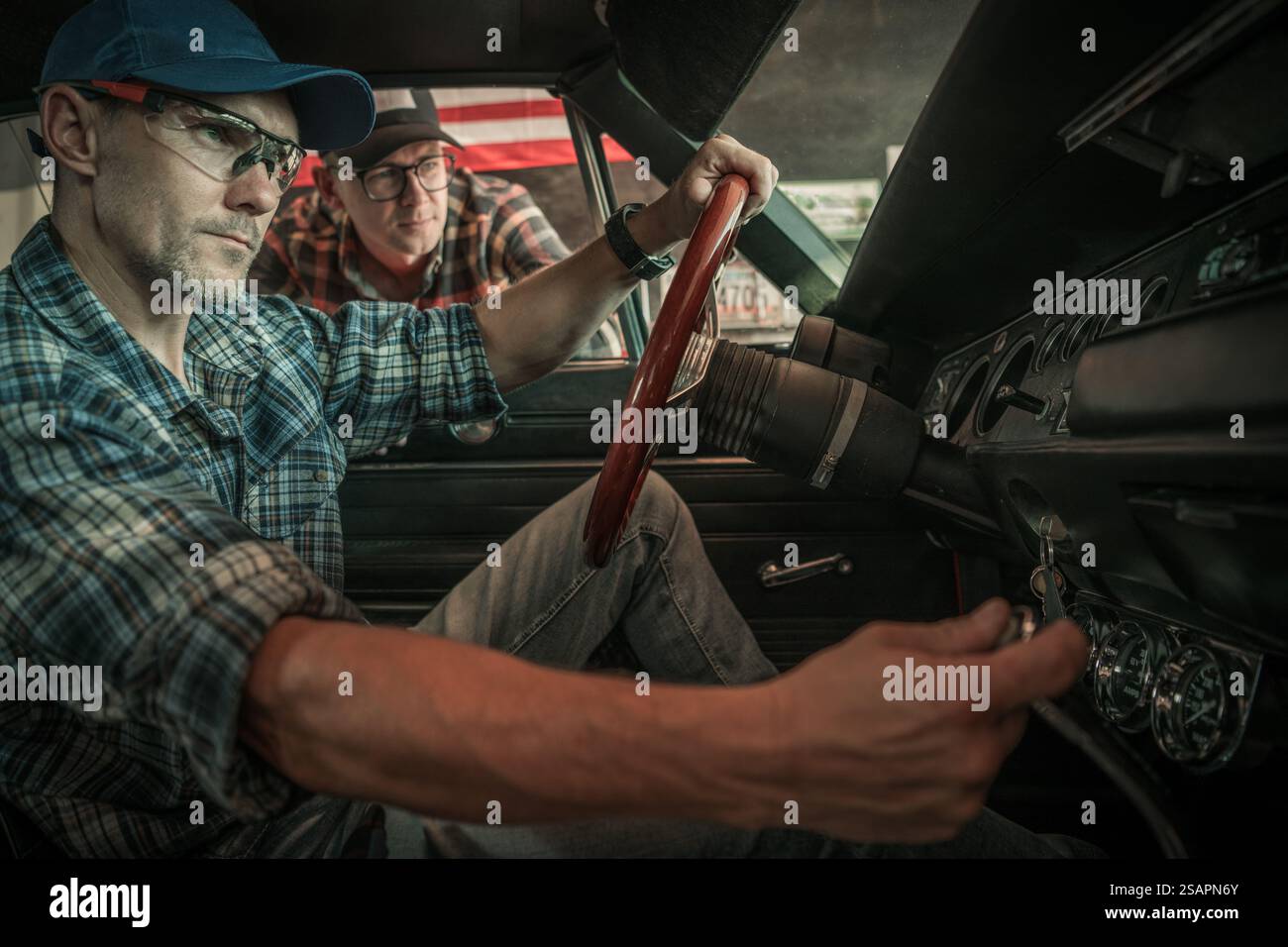 Two men are focused on repairing the dashboard of a classic car in a ...