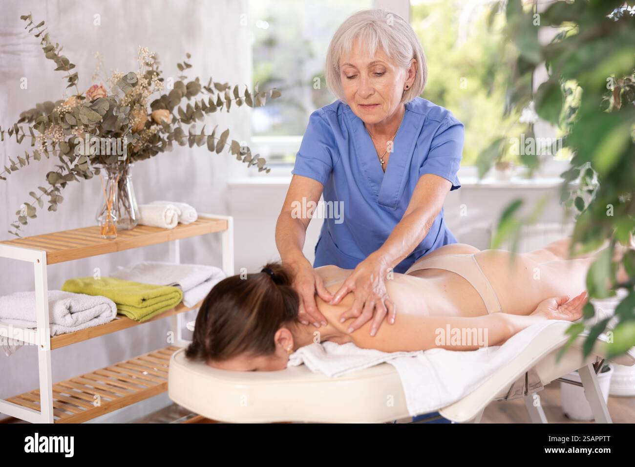Unrecognizable young woman lies face down and enjoy shoulder massage ...