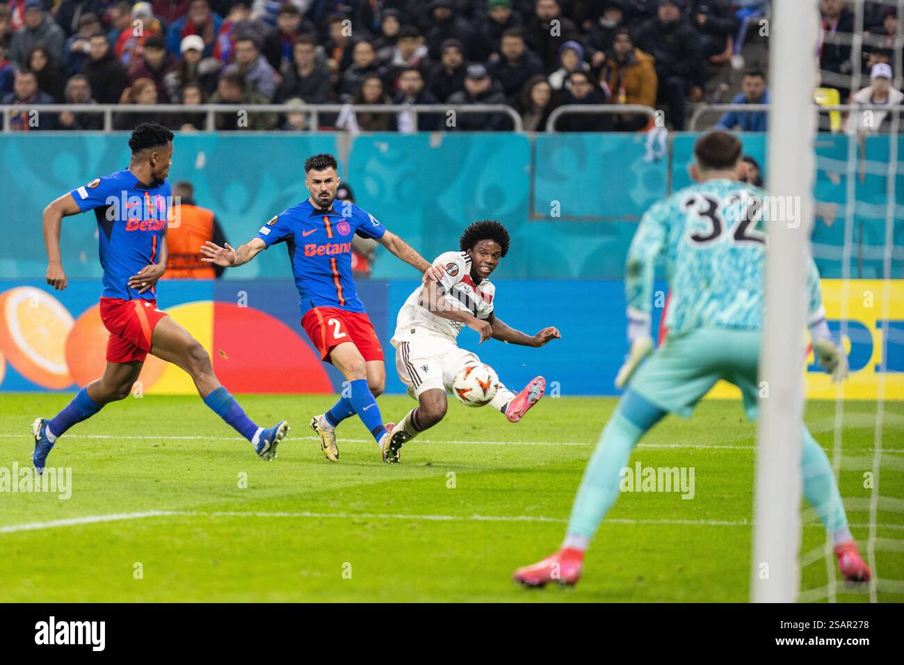 Tyrell Malacia of Manchester United shoots at goal while being tackled ...