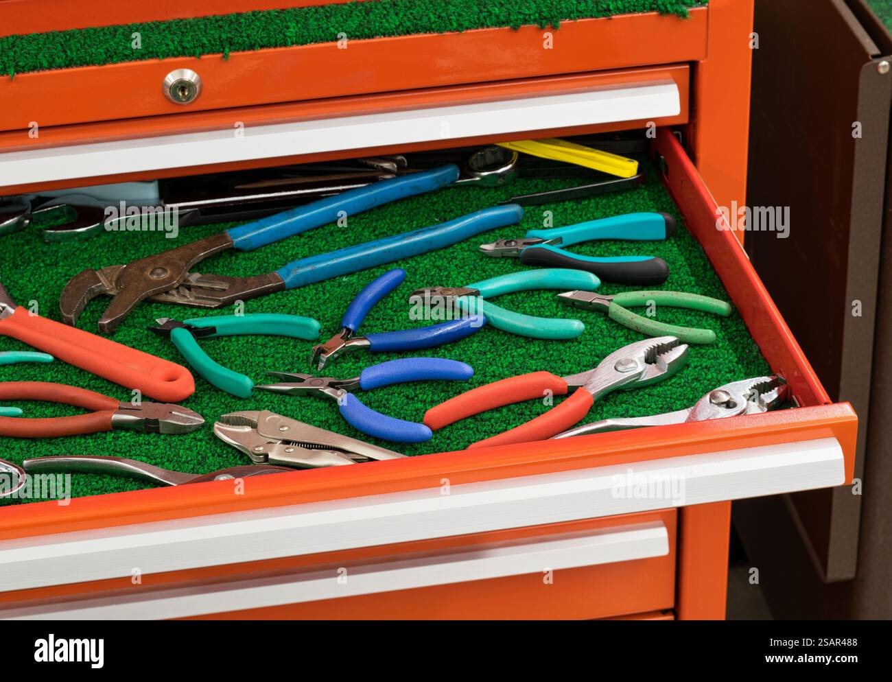 Assorted pliers wrench clamping tools displayed in open toolbox drawer ...