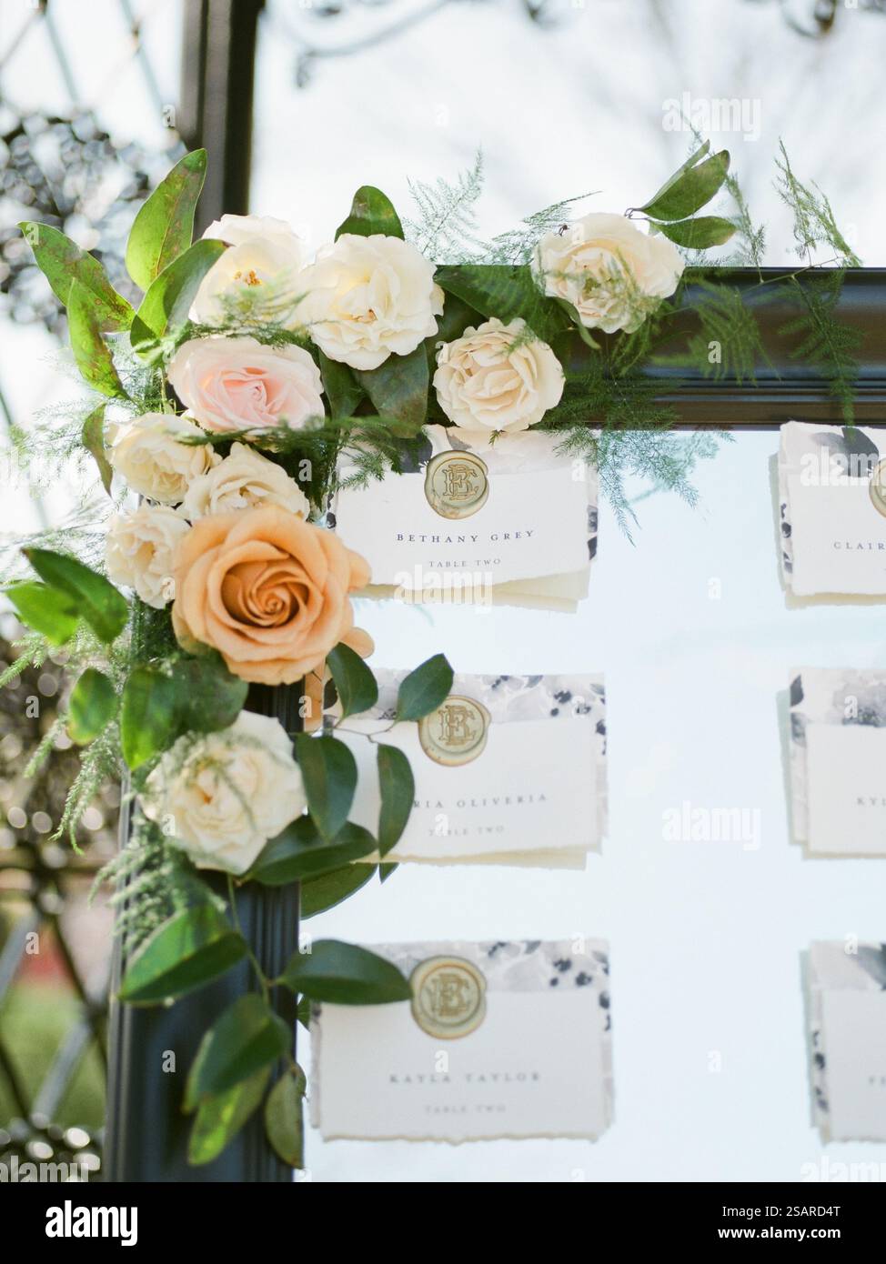 Delicate roses and greenery create a stunning border around a seating ...